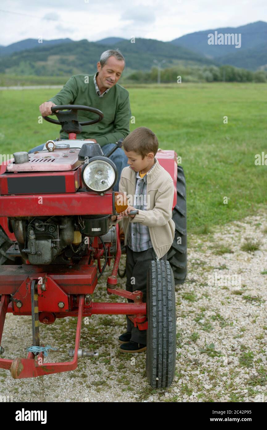 A farmer lifts his son onto a tractor Stock Photo - Alamy
