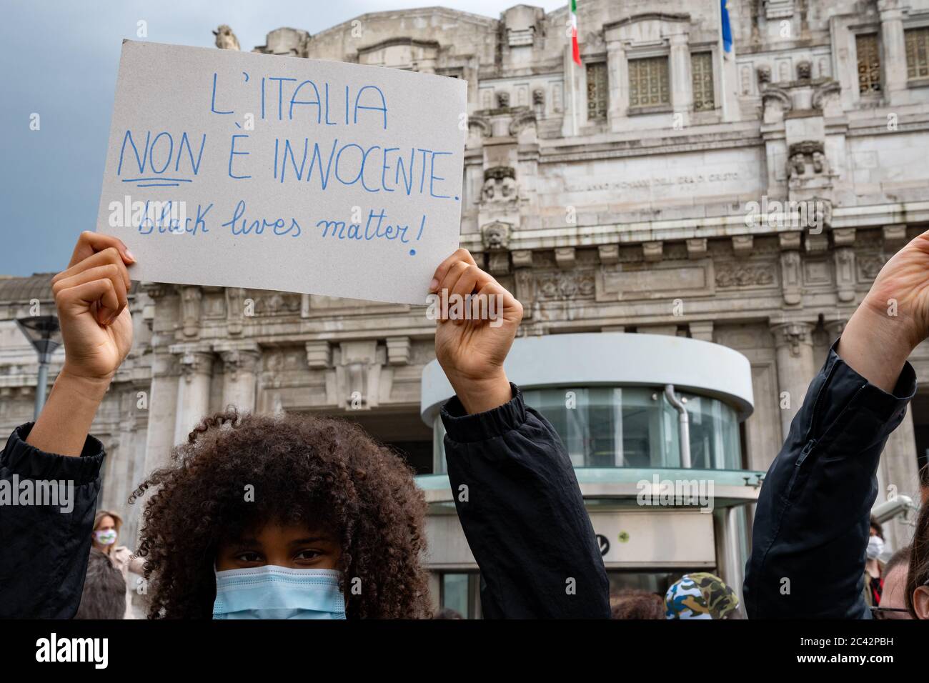 A young Afro-Italian woman holding a sign with the words "Italy is not ...