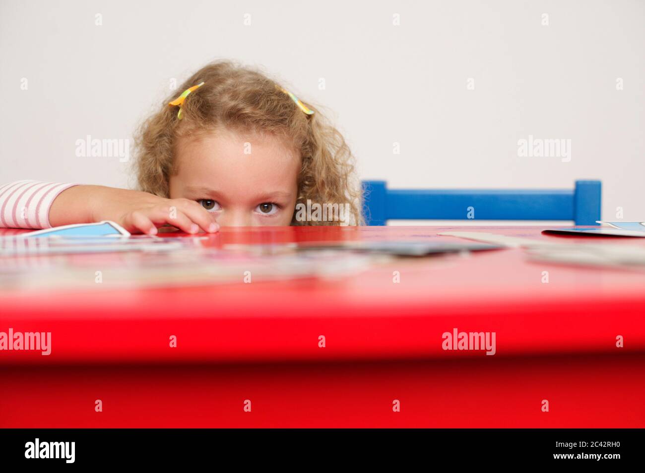 Little blonde girl peeps over the edge of the table - childhood Stock ...
