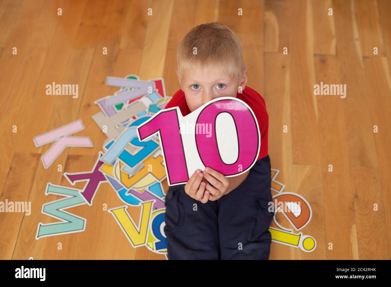 Little blond boy holds up a number - learning - numbers - letters Stock ...