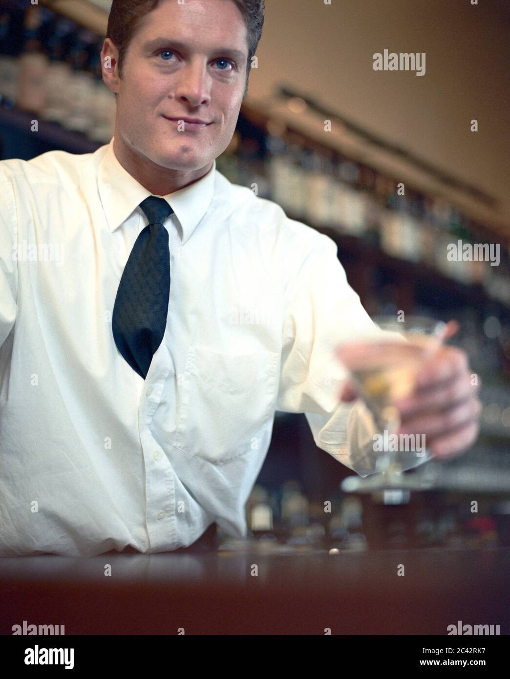 Bartender hands a drink over the bar counter Stock Photo - Alamy