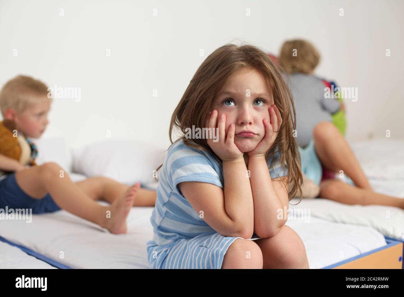 Little brown-haired girl pouting on the edge of the bed - children's ...