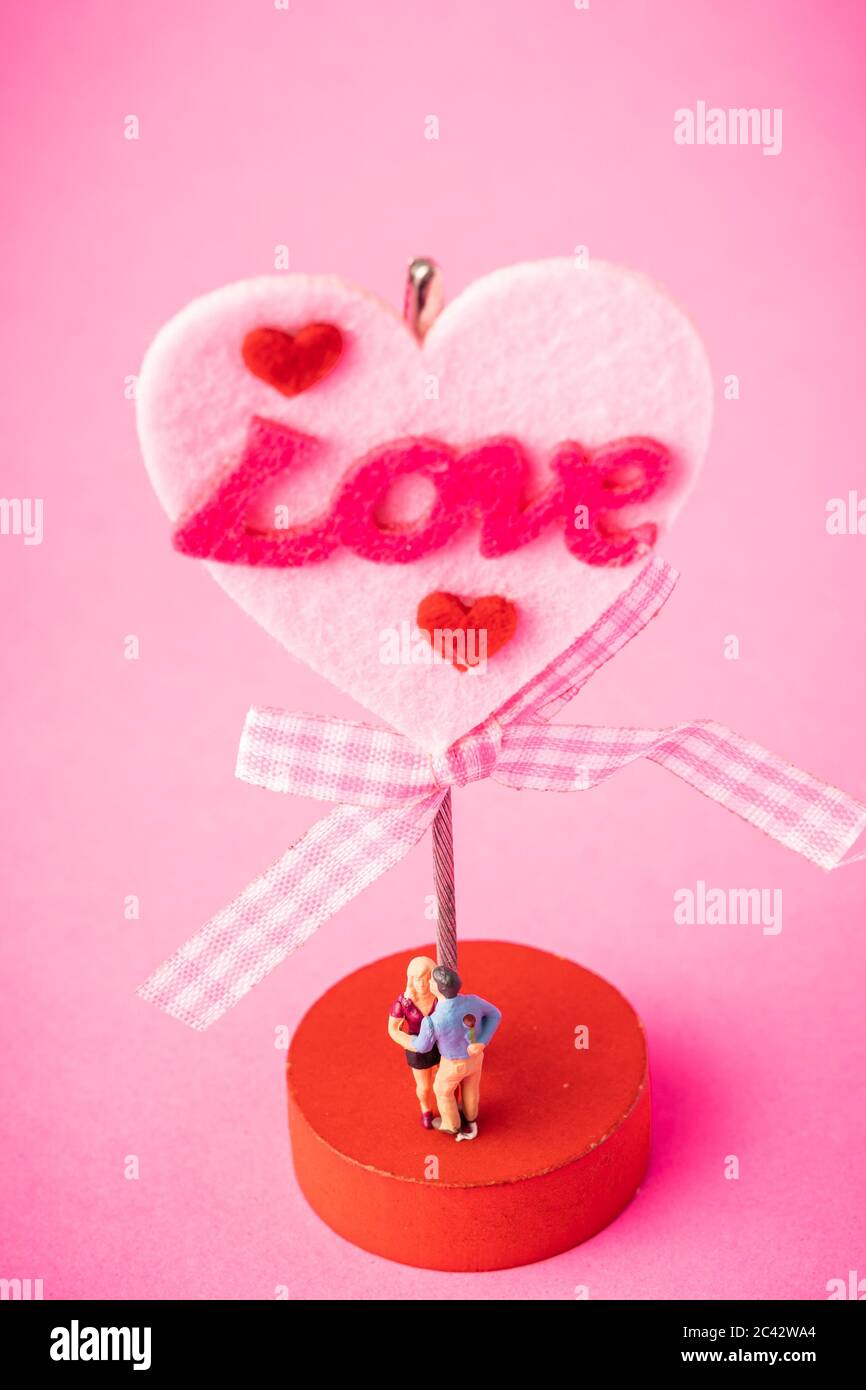 Love concept. Miniature couple against pink background Stock Photo - Alamy
