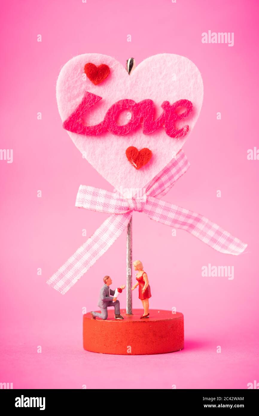 Love concept. Miniature couple against pink background Stock Photo - Alamy