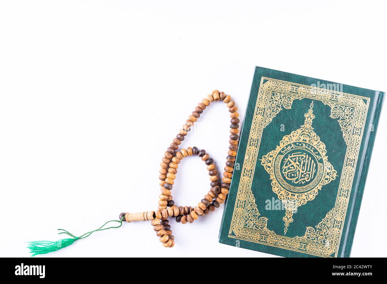 Flat lay composition of Qoran and Tasbih (rosary beads). The words on ...