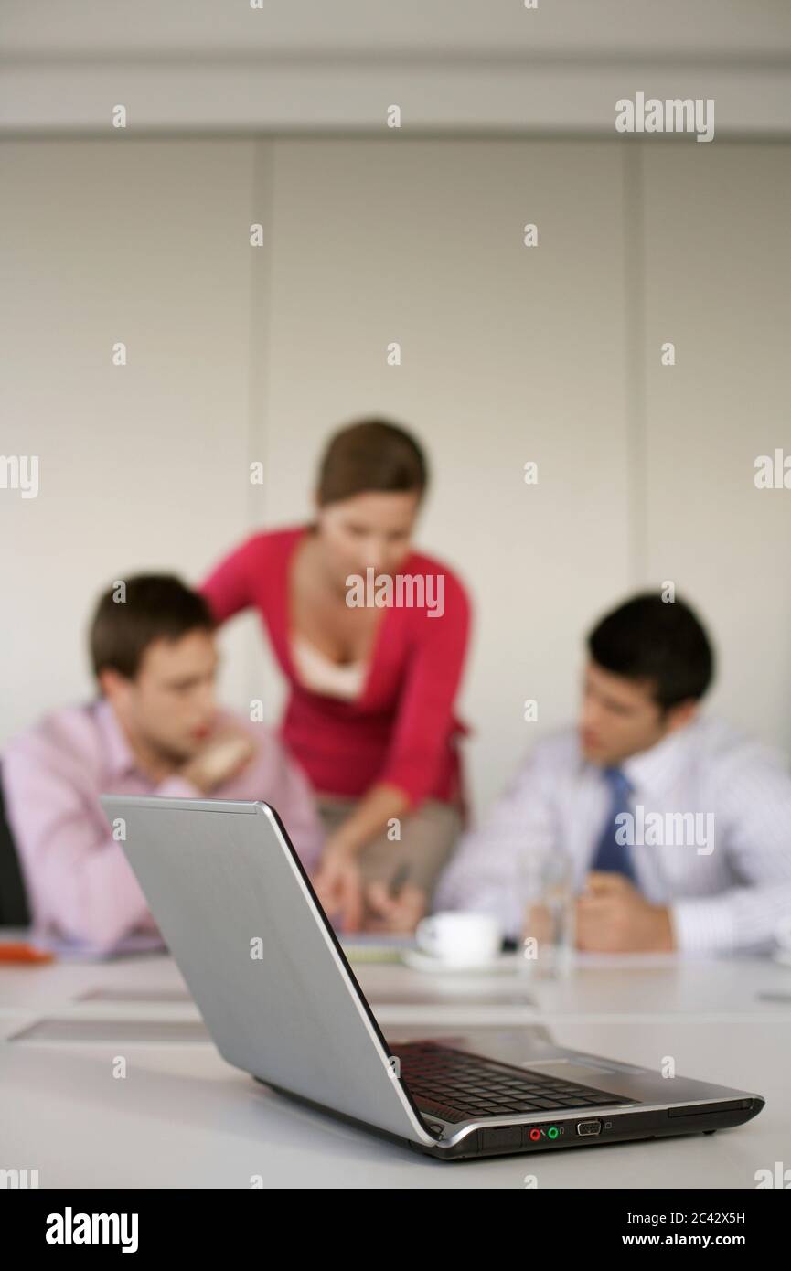 Woman bends over a table with two businessmen - office - teamwork Stock ...