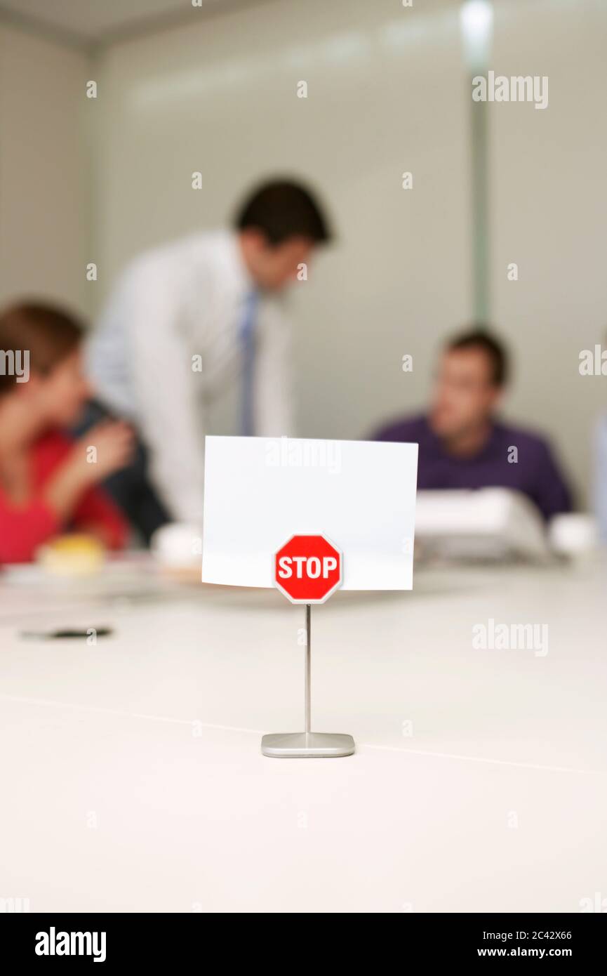 Stop sign at a photo holder in front of business people on the table ...