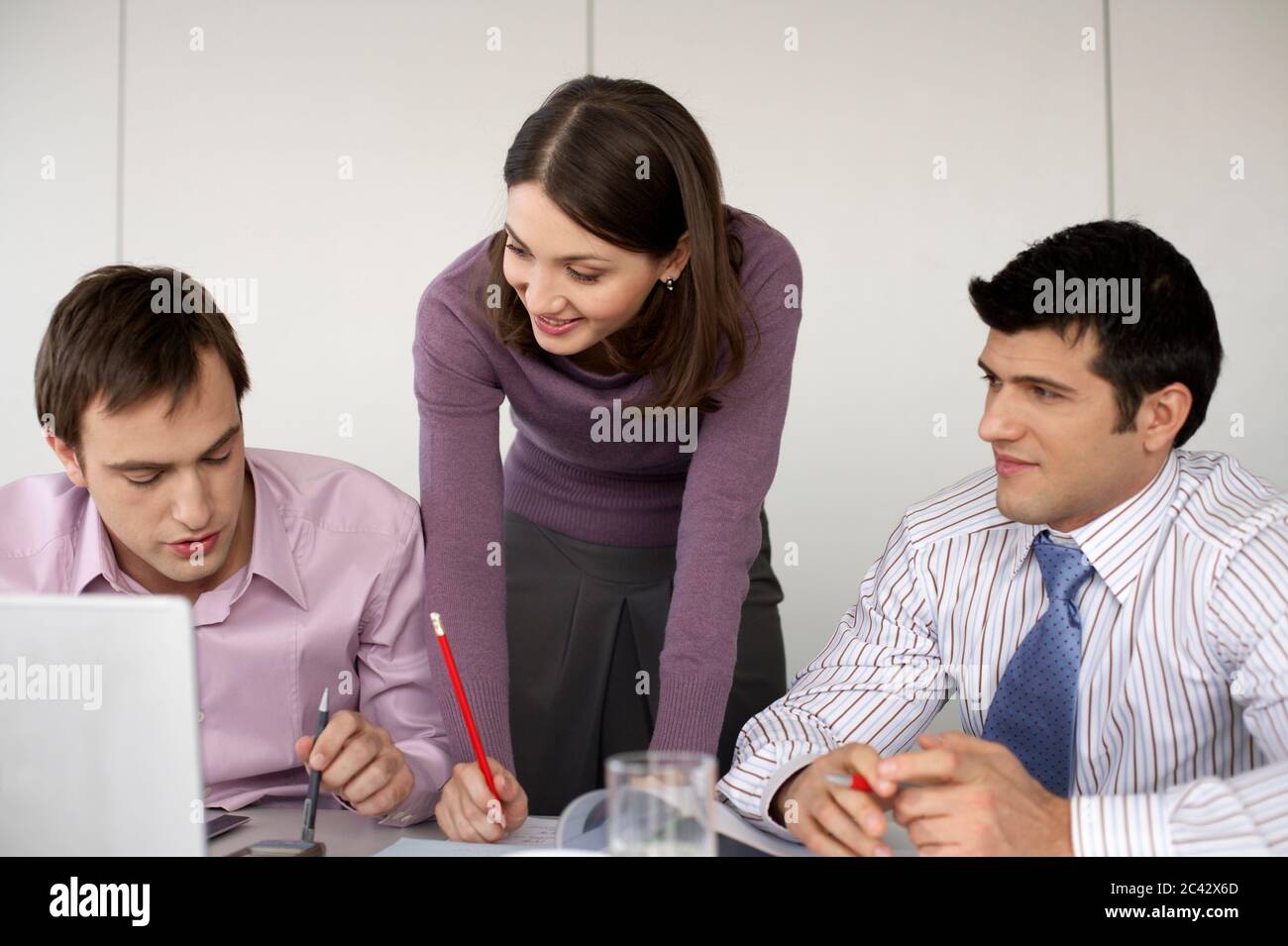 Woman bends over a table with two businessmen - office - teamwork Stock ...