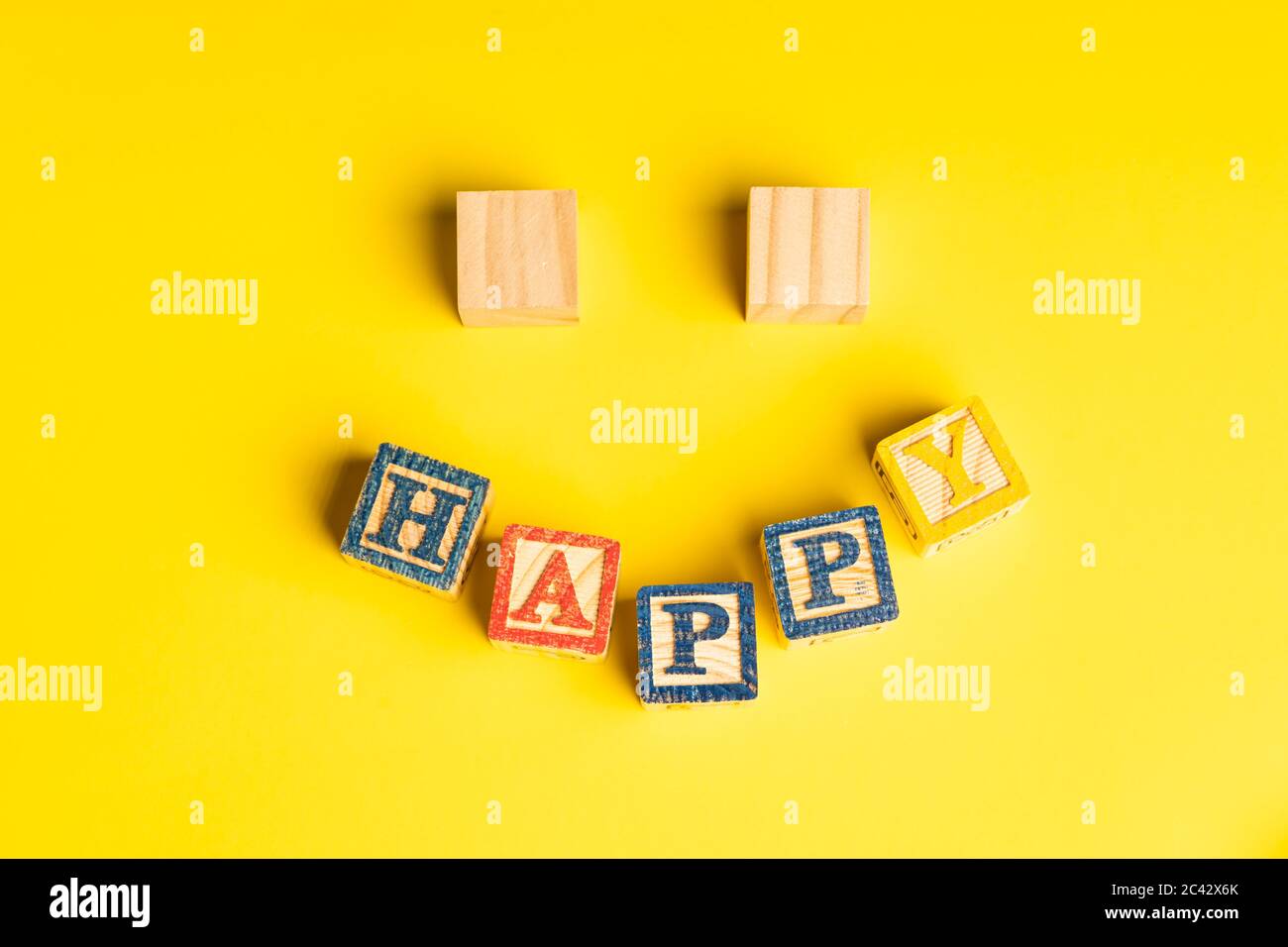 wooden blocks forming a smiling face against yellow background with ...