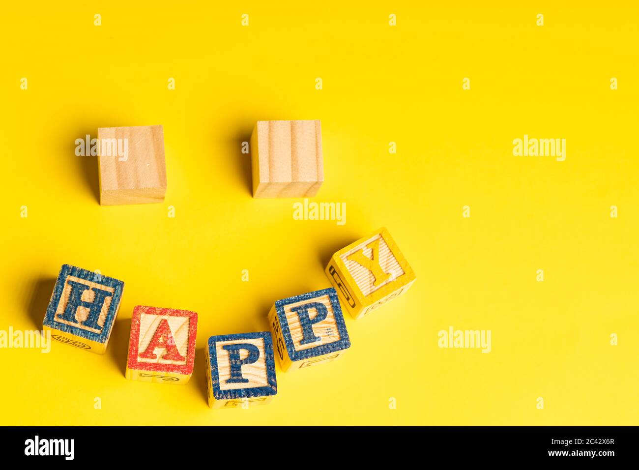 wooden blocks forming a smiling face against yellow background with ...