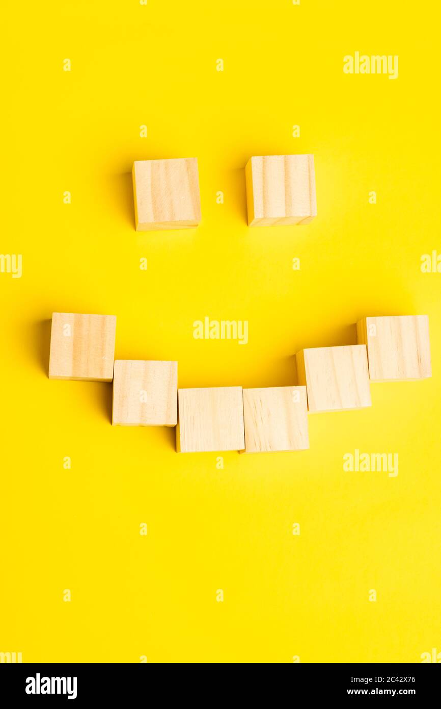 wooden blocks forming a smiling face against yellow background with ...