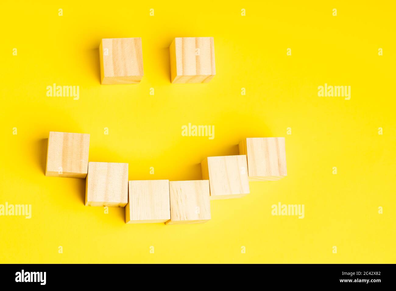 wooden blocks forming a smiling face against yellow background with ...