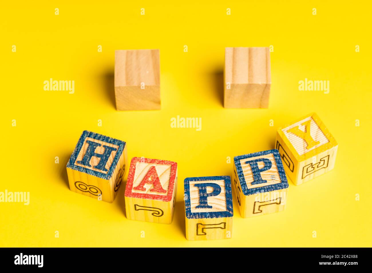 wooden blocks forming a smiling face against yellow background with ...