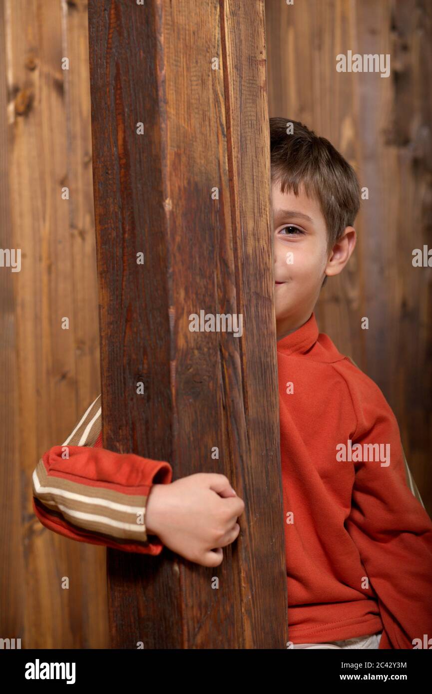 Little boy is hiding behind a wooden pillar - hide-and-seek - childhood ...