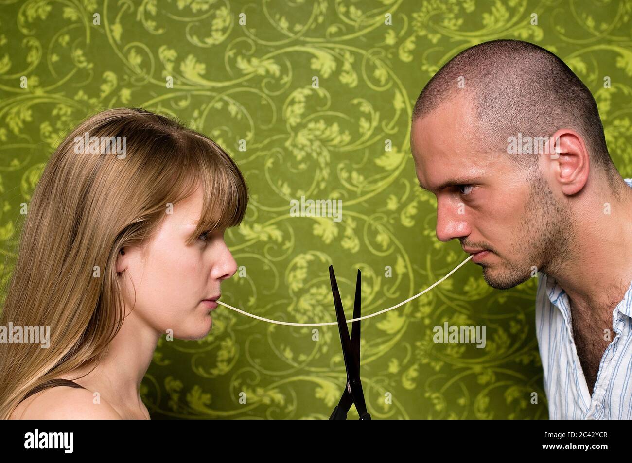 Couple shares a spaghetti, woman holds scissors Stock Photo - Alamy
