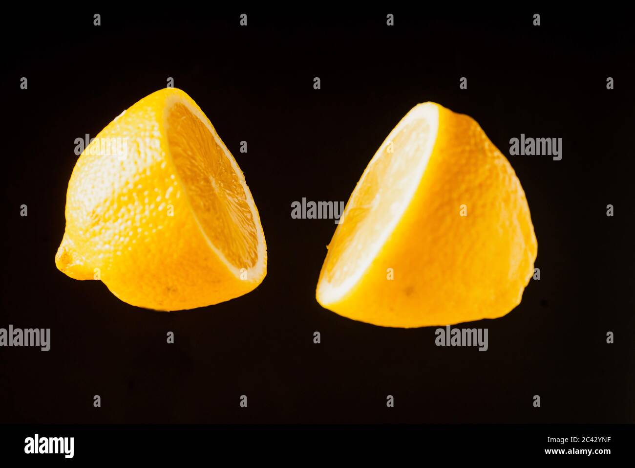 Sliced lemon floating against black background Stock Photo - Alamy