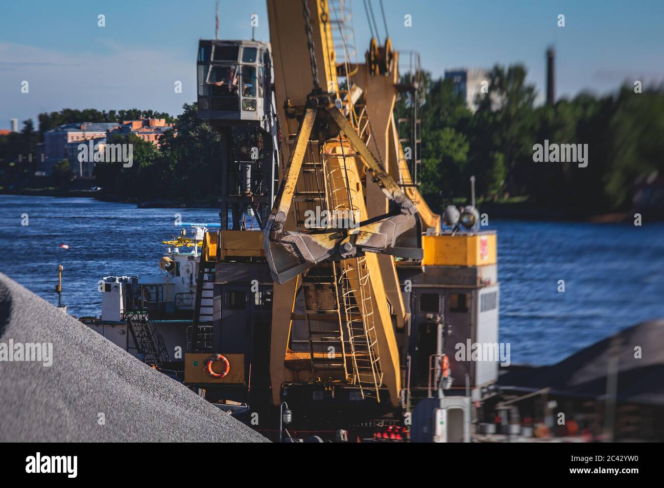 Bulk-handling crane unloading sand, road metal and gravel from cargo ...