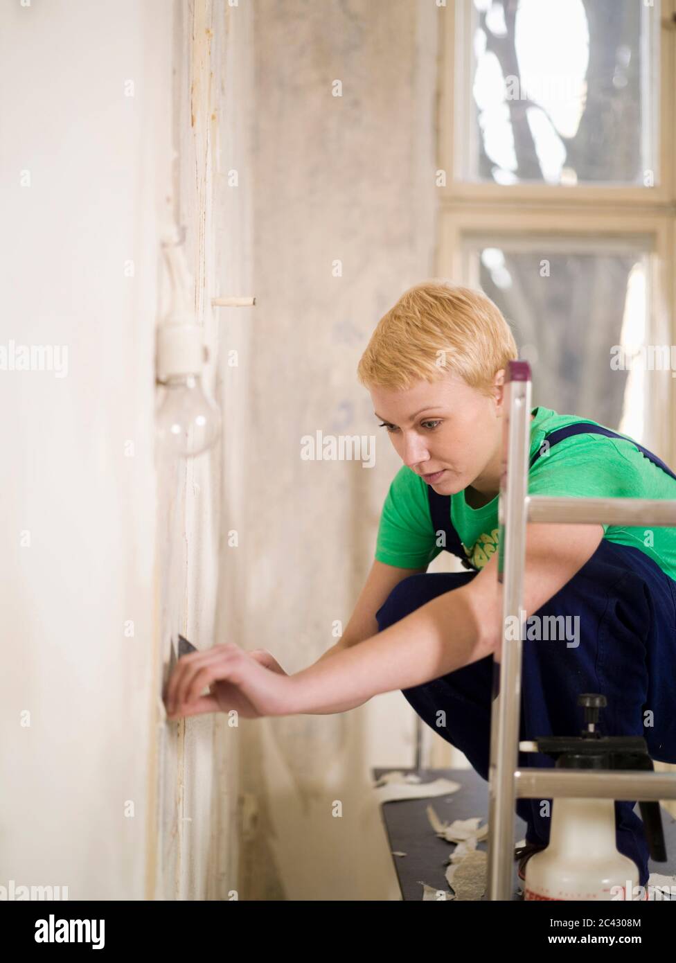 Young woman scratches wallpaper from a wall Stock Photo - Alamy