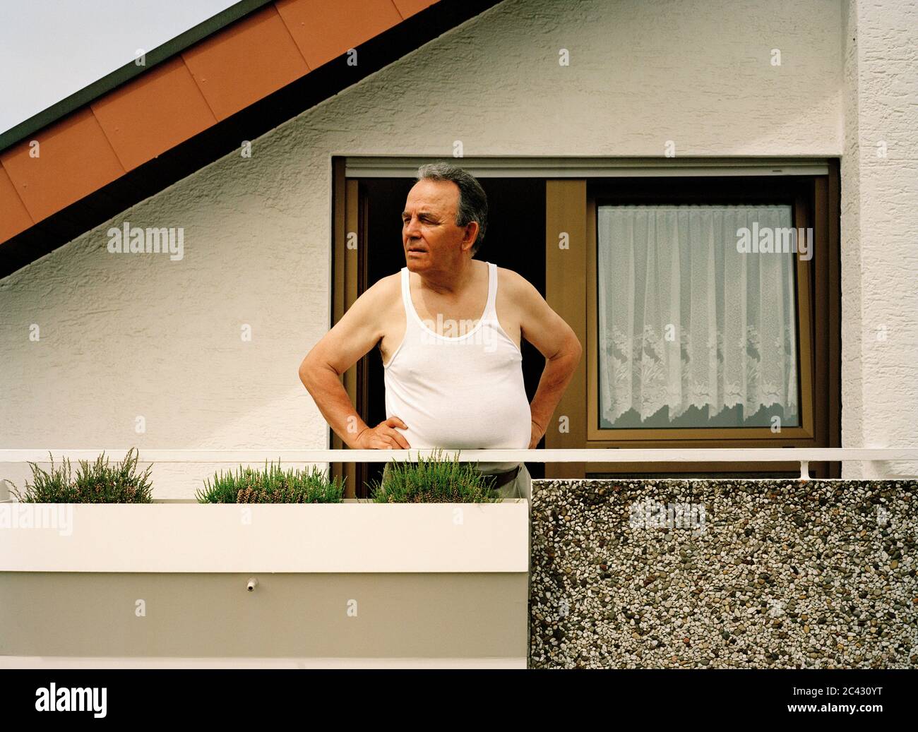 Old man stands on the balcony and looks down Stock Photo - Alamy