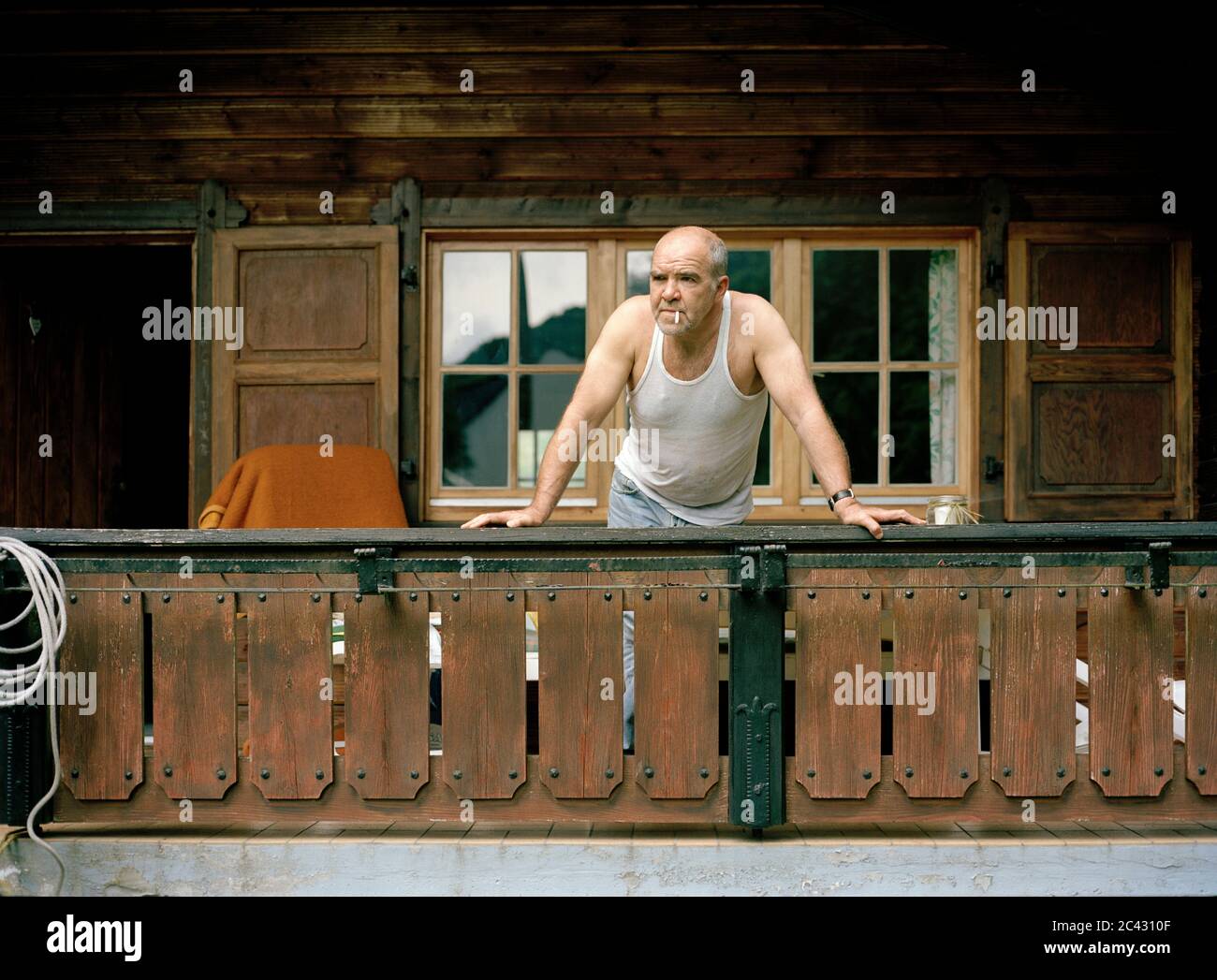 Old man stands on the balcony and looks down Stock Photo - Alamy