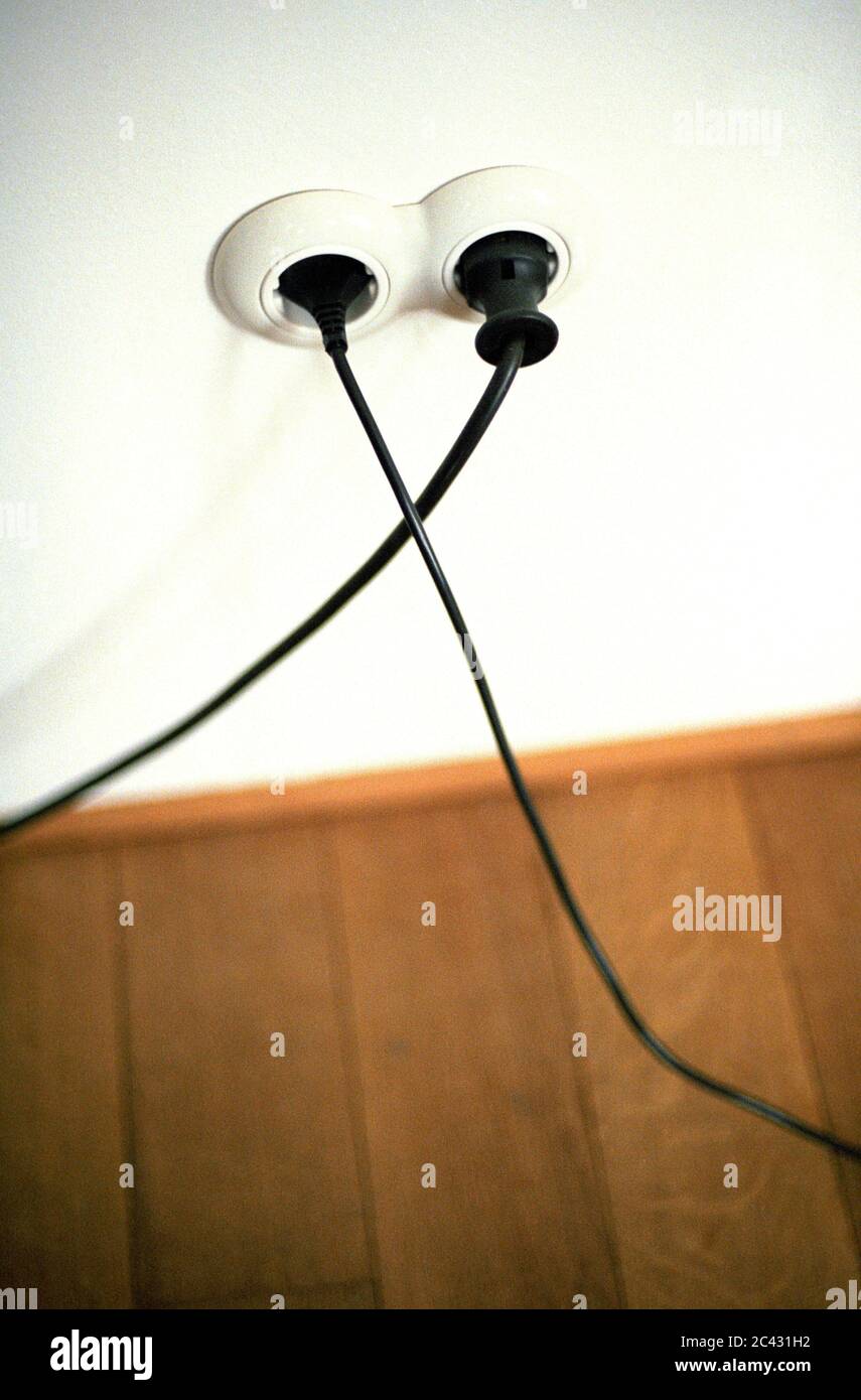 Two plugs cross over into sockets - electricity Stock Photo - Alamy