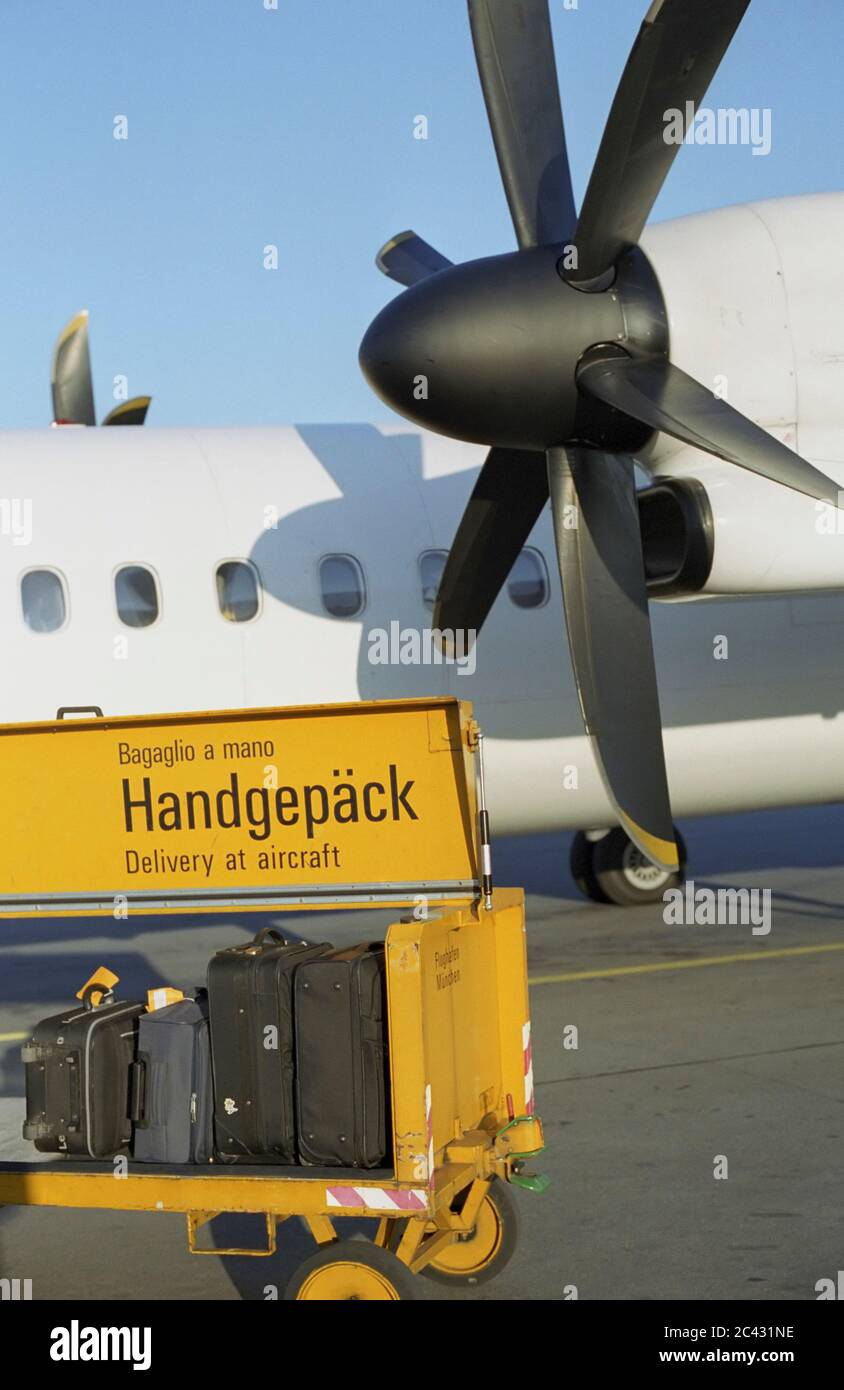A cart for hand luggage in front of a propeller plane - transportation ...