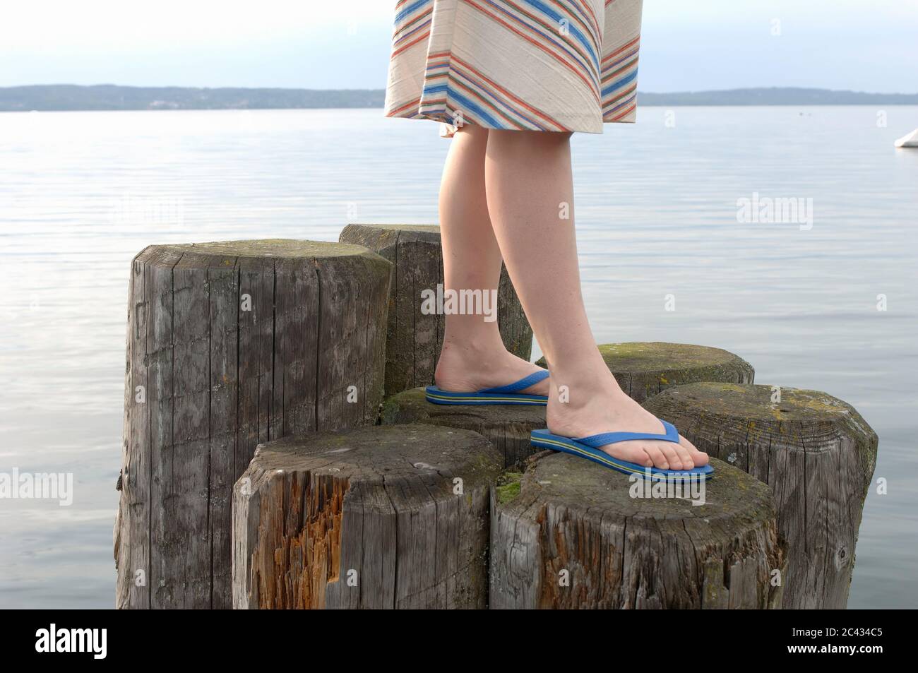 Woman in flip-flops stands on tree trunks in the lake Stock Photo - Alamy