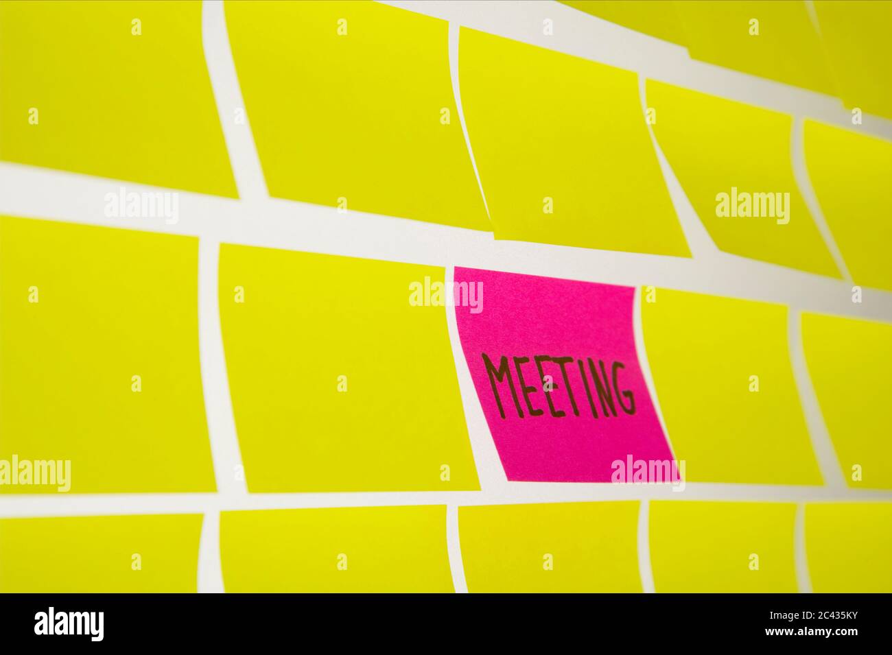 Pink sticky note with the word meeting between yellow sticky notes ...