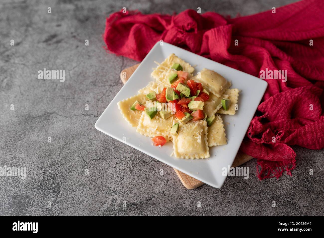 Creative cheese ravioli topped with fresh tomato and avocado and ...