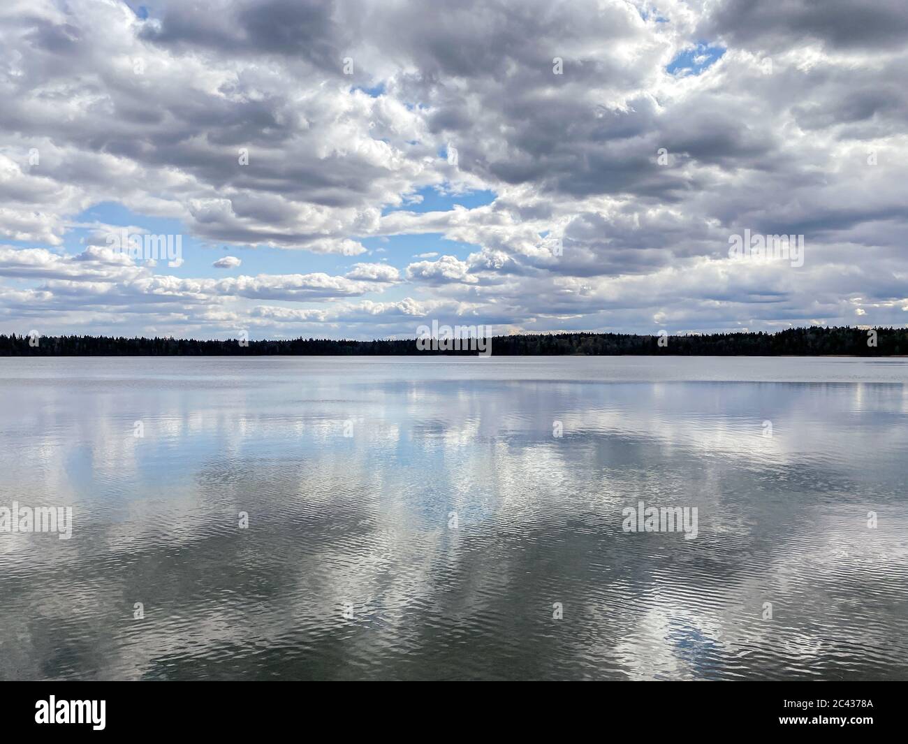 lake landscape with blue sky and dark storm clouds reflection in the ...