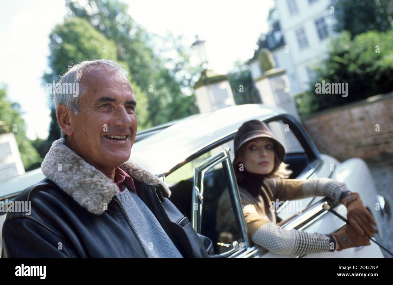 Blond woman in a hat leans out the window of a classic car - nobility ...