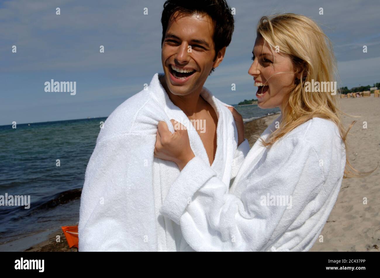 Couple in bathrobe hugging each other on the beach Stock Photo - Alamy