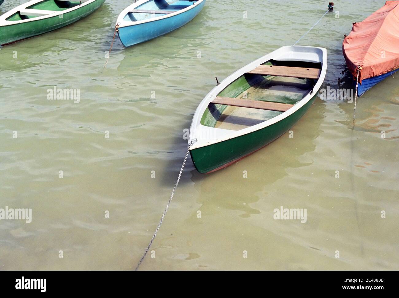 Four rowboats chained to the shore Stock Photo - Alamy