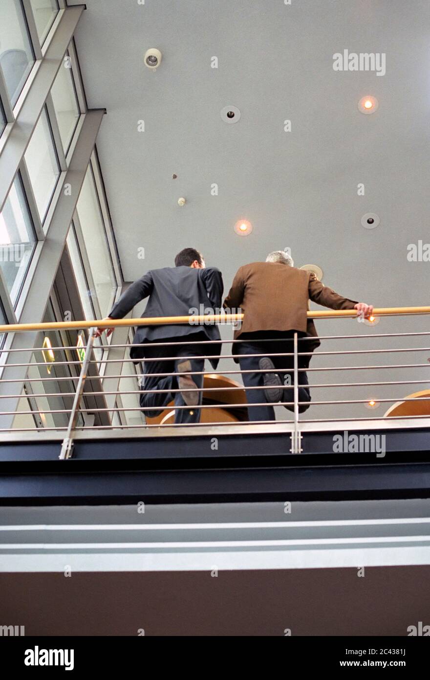 Two businessmen lean against a railing - conversation - business ...