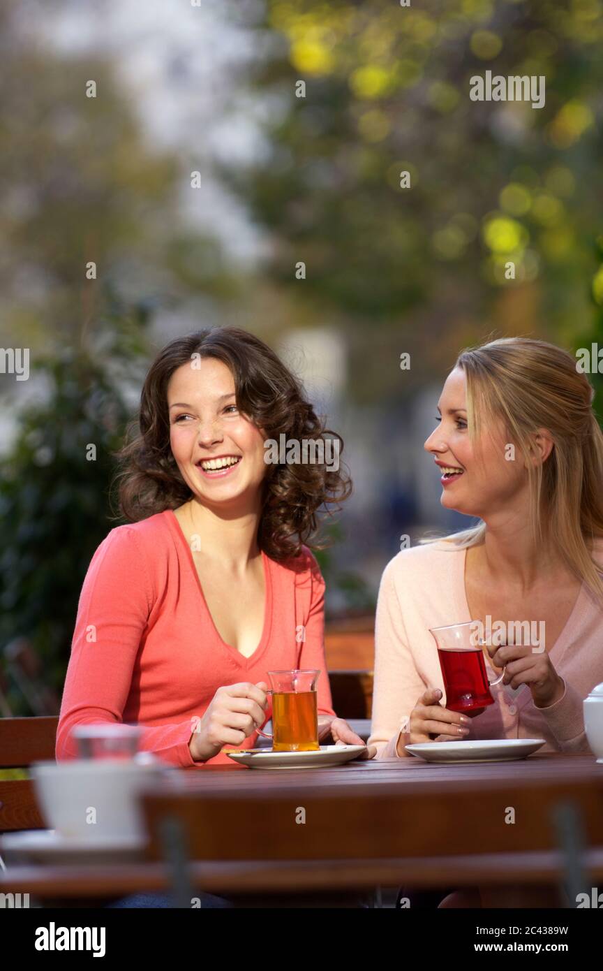 Two women drink tea in a street cafe Stock Photo - Alamy