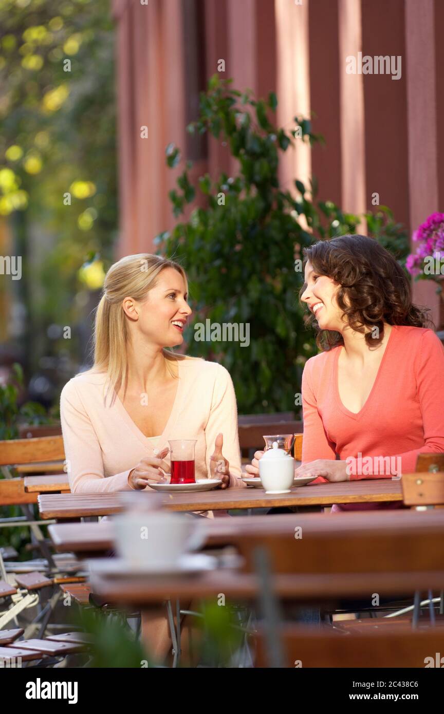 Two women are sitting in a street cafe drinking tea Stock Photo - Alamy