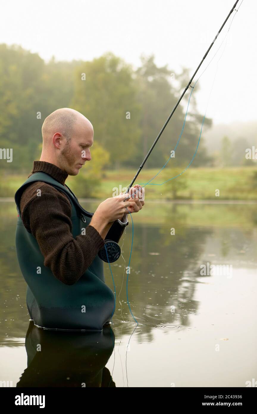Angler in the water checks the bait on the fishing rod Stock Photo - Alamy