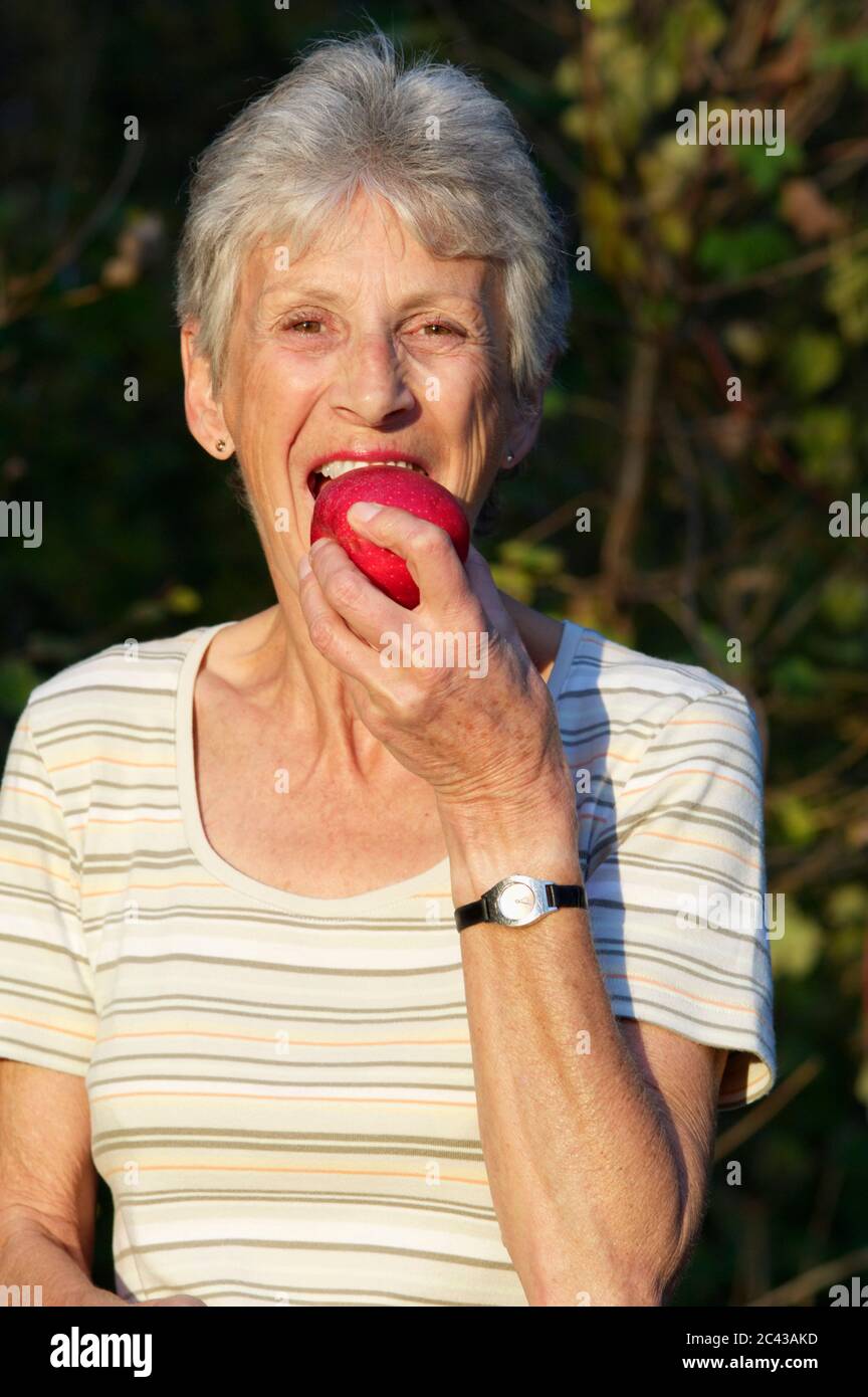 Old woman bites an apple Stock Photo - Alamy