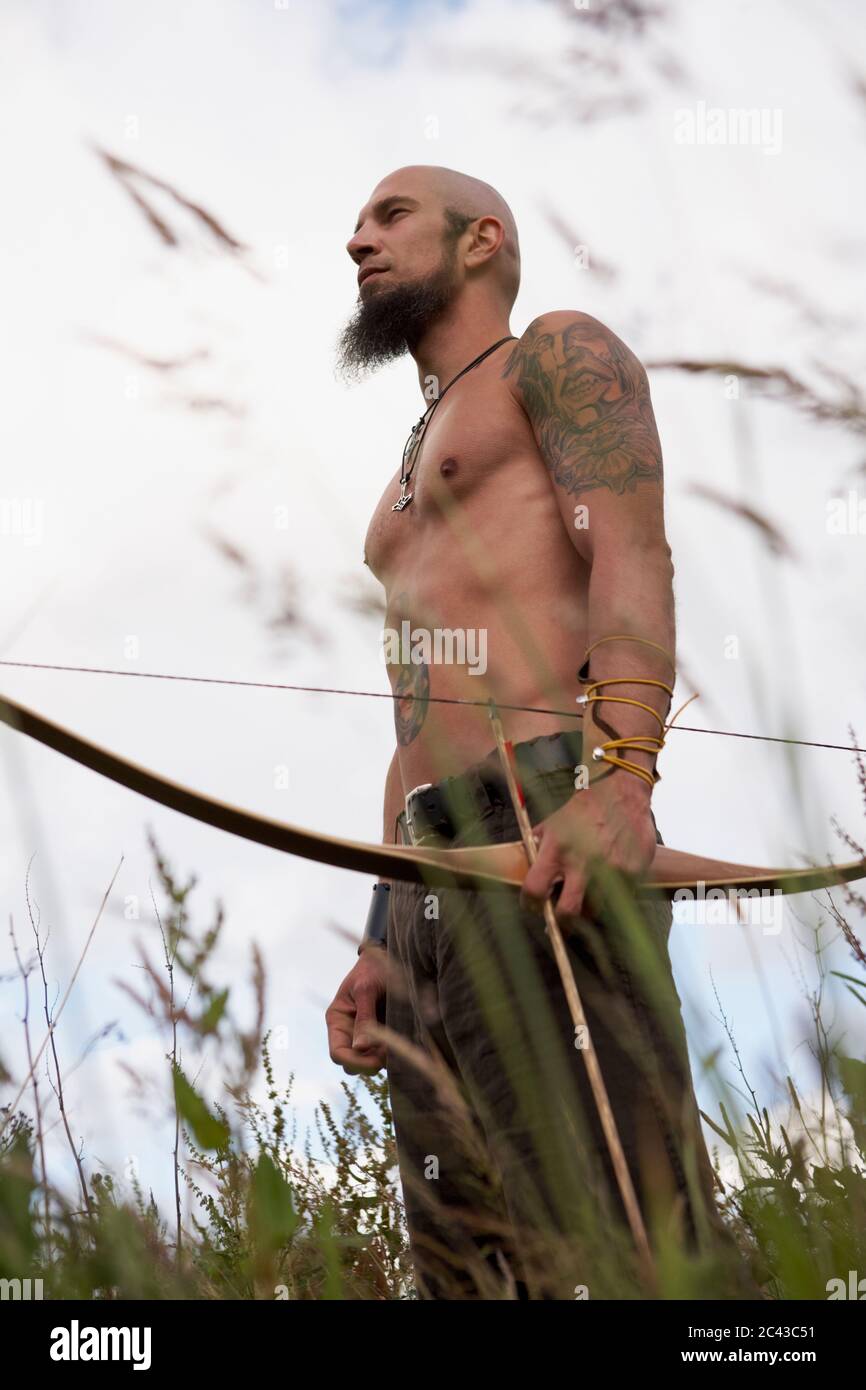 Archer with a bow and arrow in a field Stock Photo - Alamy
