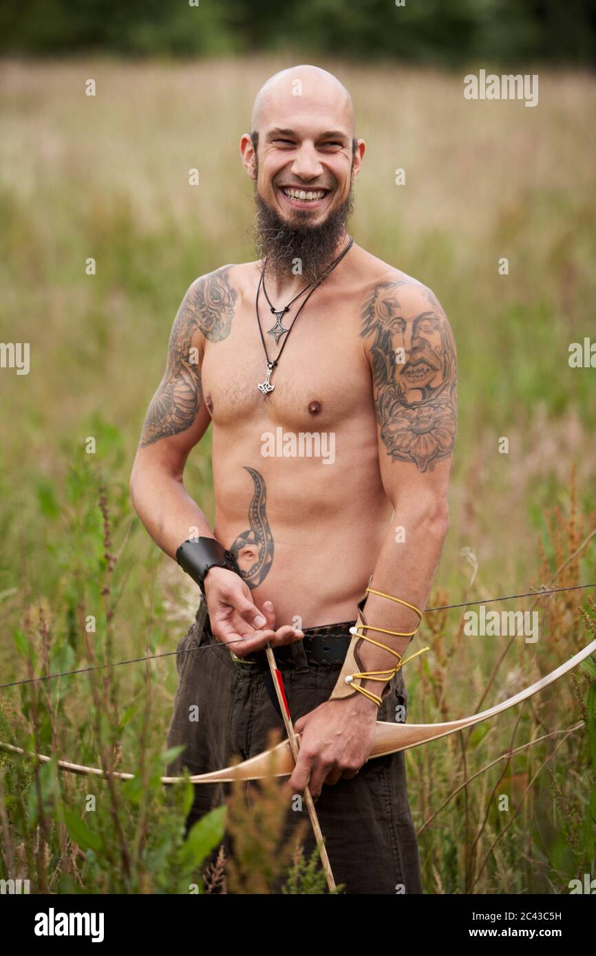 Archer with a bow and arrow in a field Stock Photo - Alamy