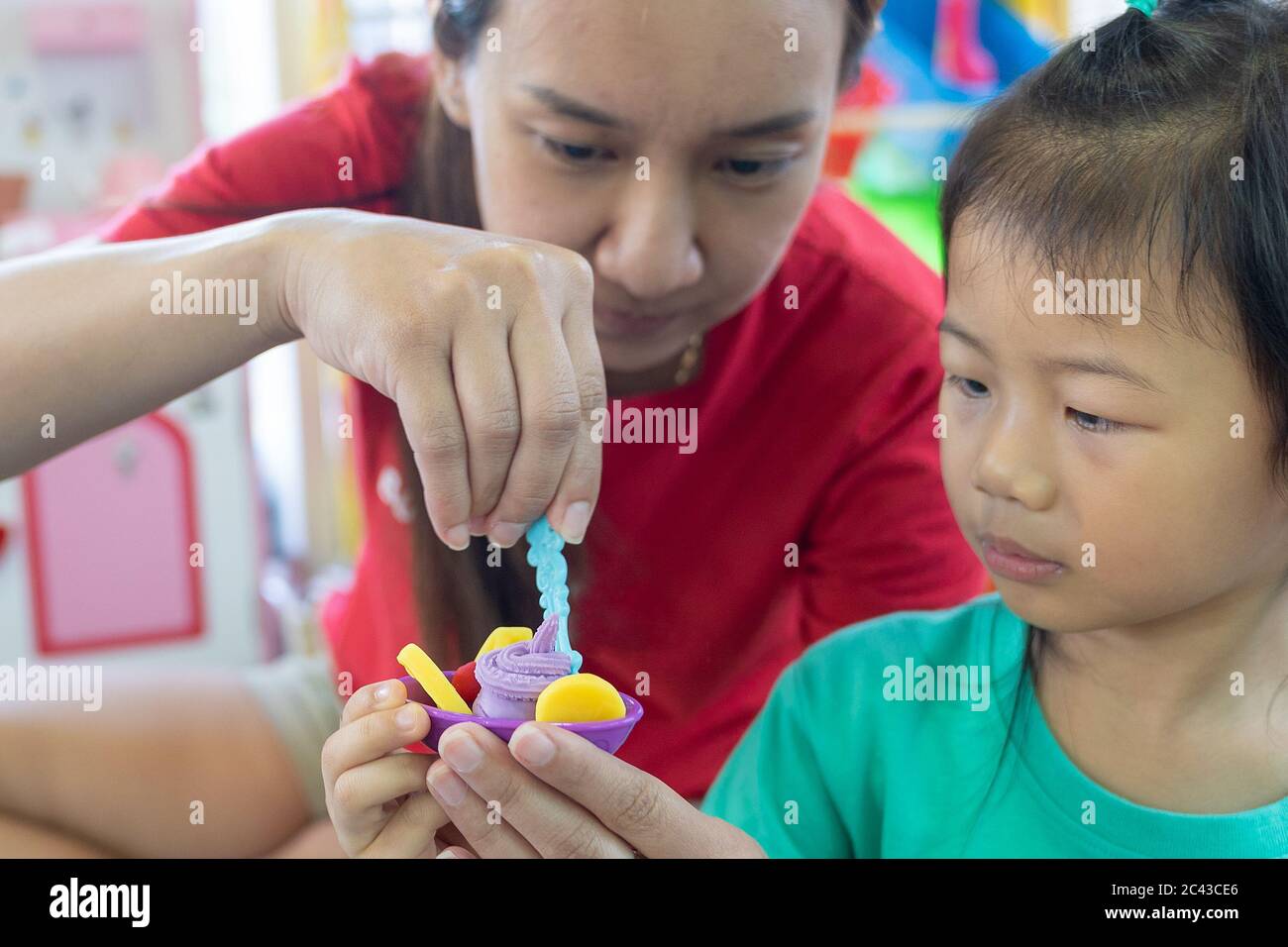 Asian young mom stay at home play with plasticine modeling clay with little daughter, happy ...