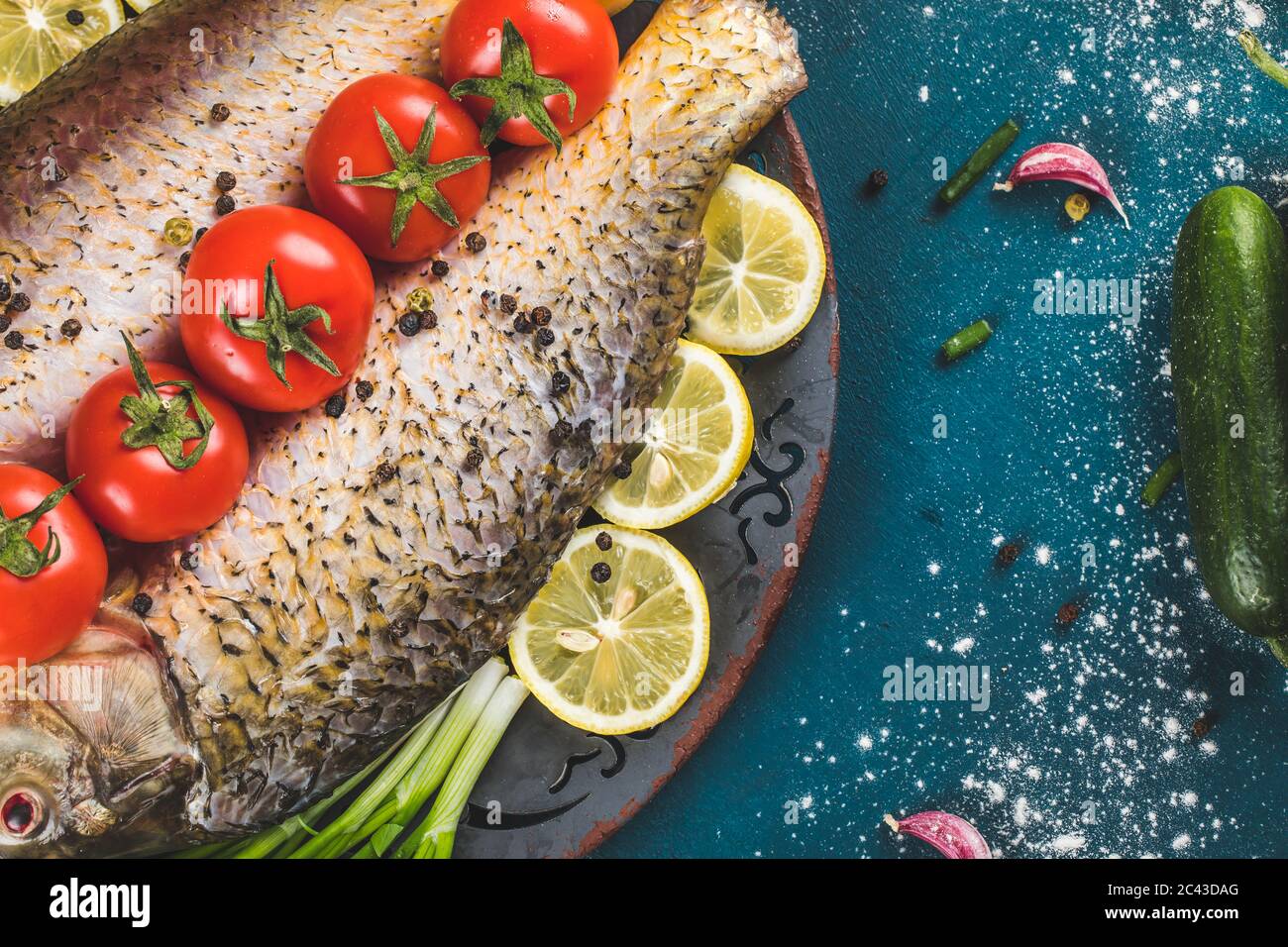 Raw fish fillet with herbs and vegetables in a rustic platter with ...