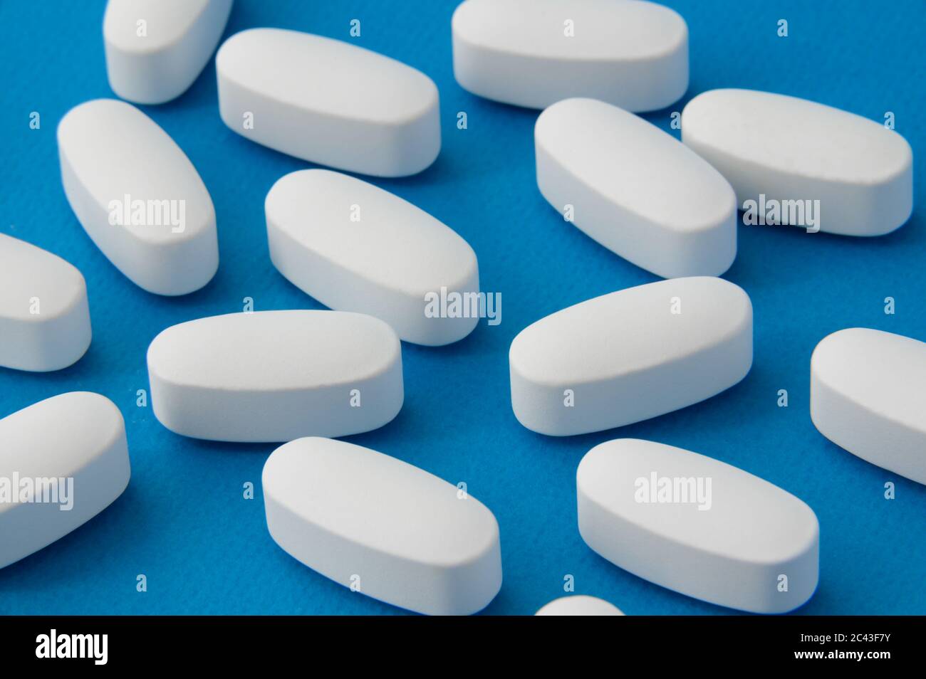 pure clean white chemical pharmacological tablets lying on blue surface ...