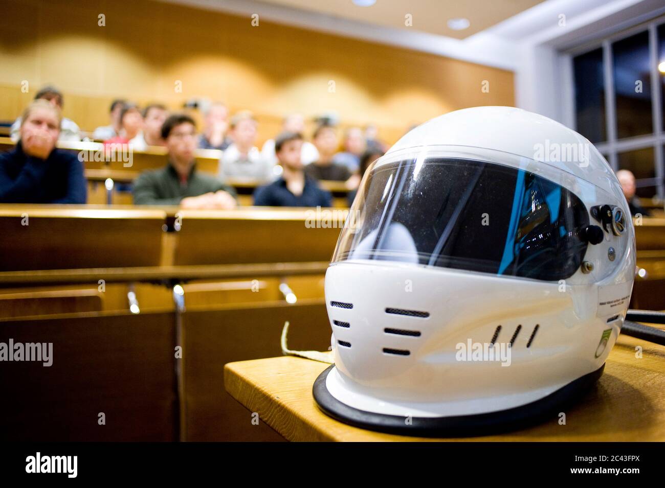 Motorcycle helmet on desk in lecture hall with students in the ...