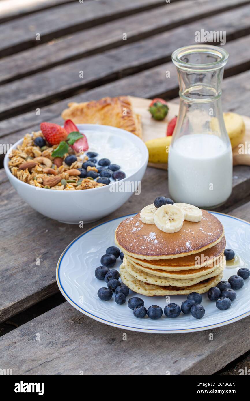 Breakfast table with pancake, granola yogurt, fresh berries and milk ...