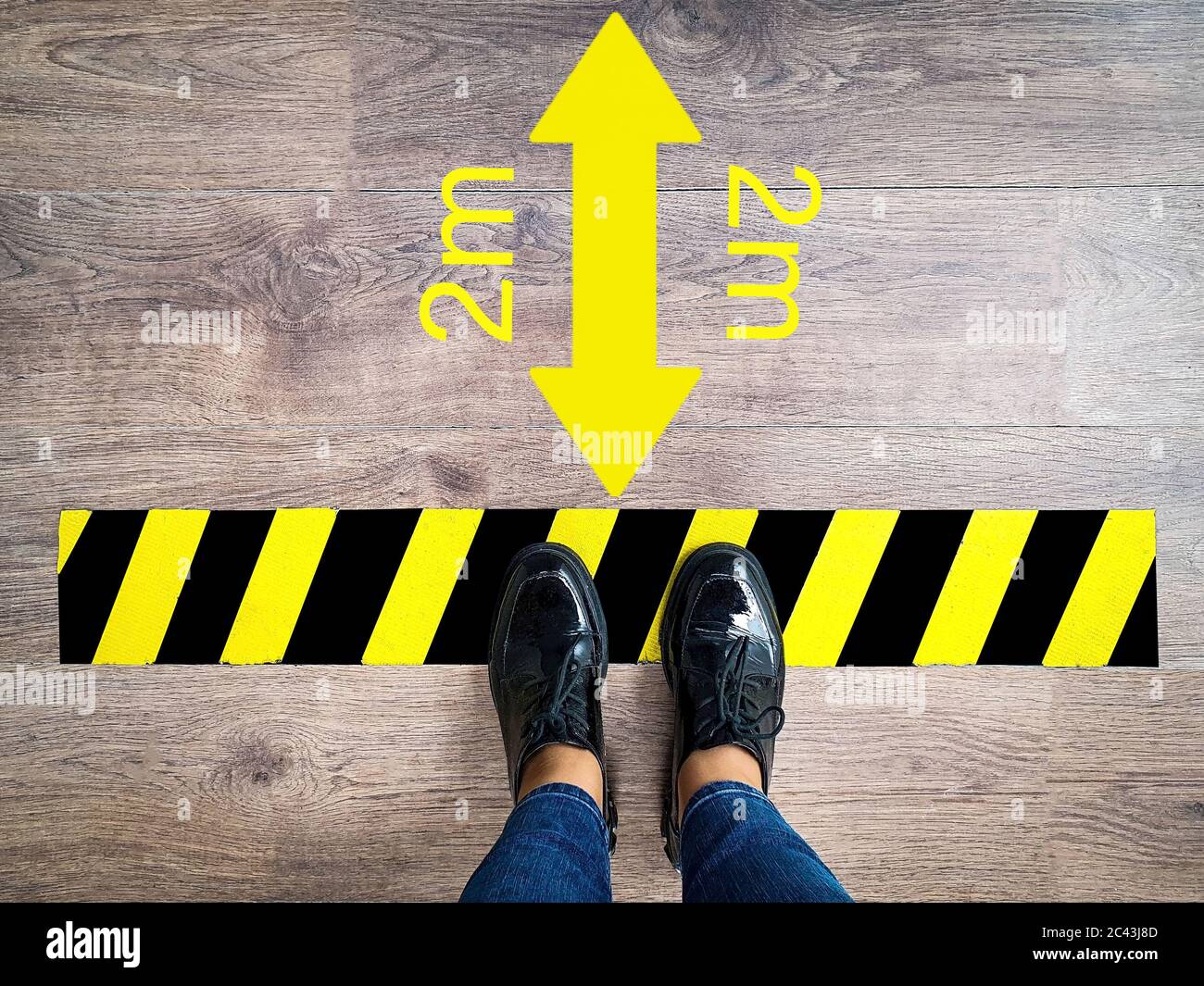person stands in line with yellow and black stripes keeping safe social ...