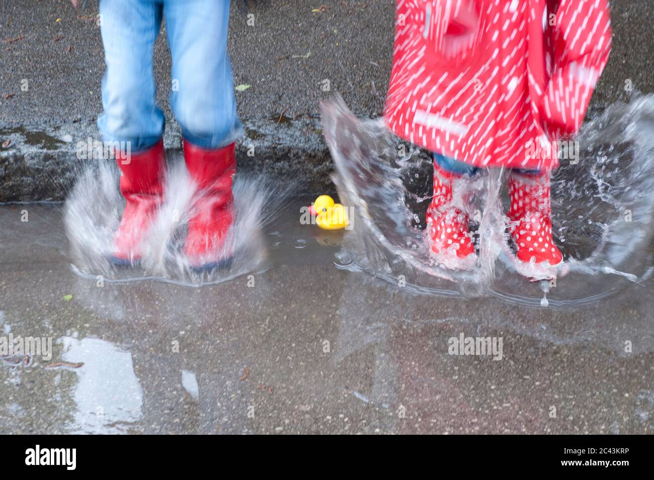 Two children jump in a puddle, close-up Stock Photo - Alamy