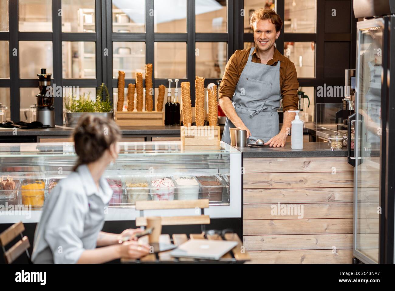 Working staff at the cafe or pastry shop, waiter sitting with phone and ...