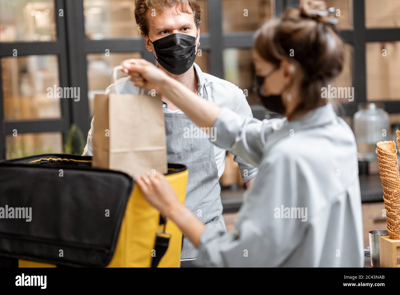 Female courier taking online order for delivery at the counter with ...