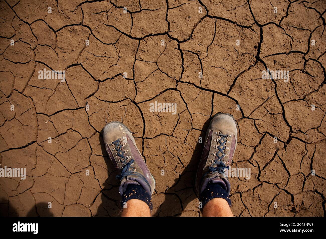 Man wears walking shoes on parched ground Stock Photo - Alamy